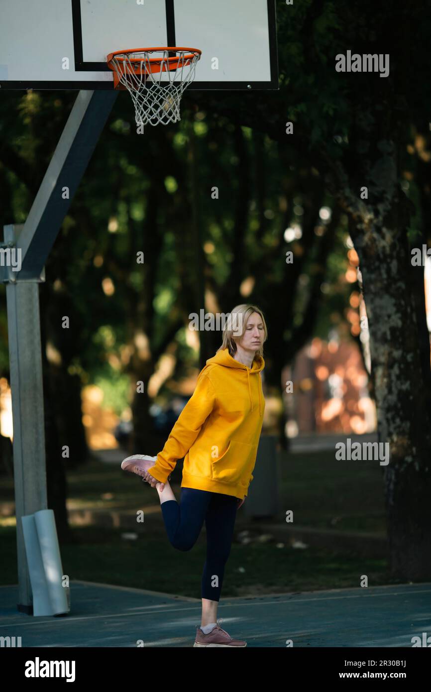 A woman warming up before a jog on an outdoor basketball court Stock ...