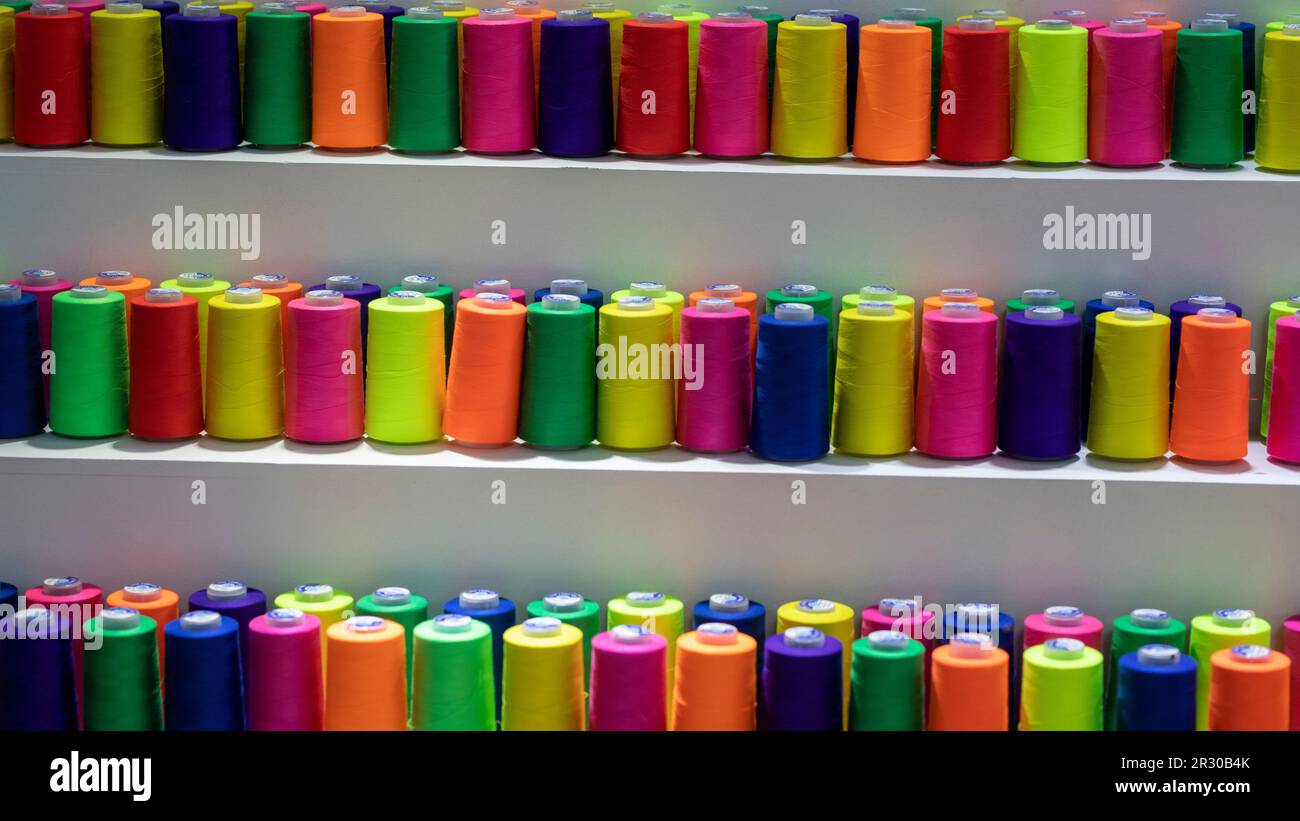 Spools of colorful thread lined in rows are in display at a stall of ...