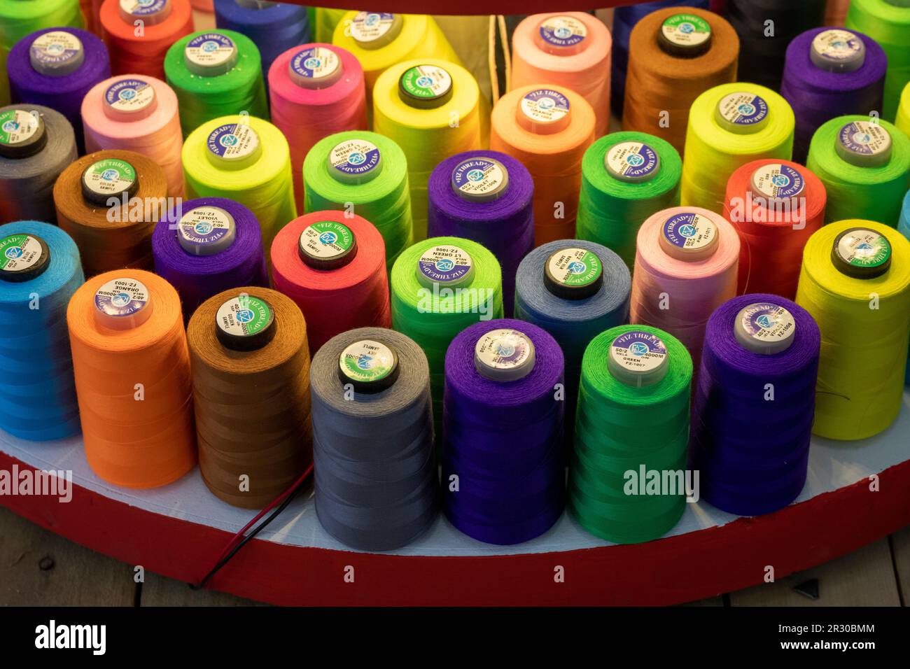 Spools of colorful thread lined in rows are in display at a stall of ...
