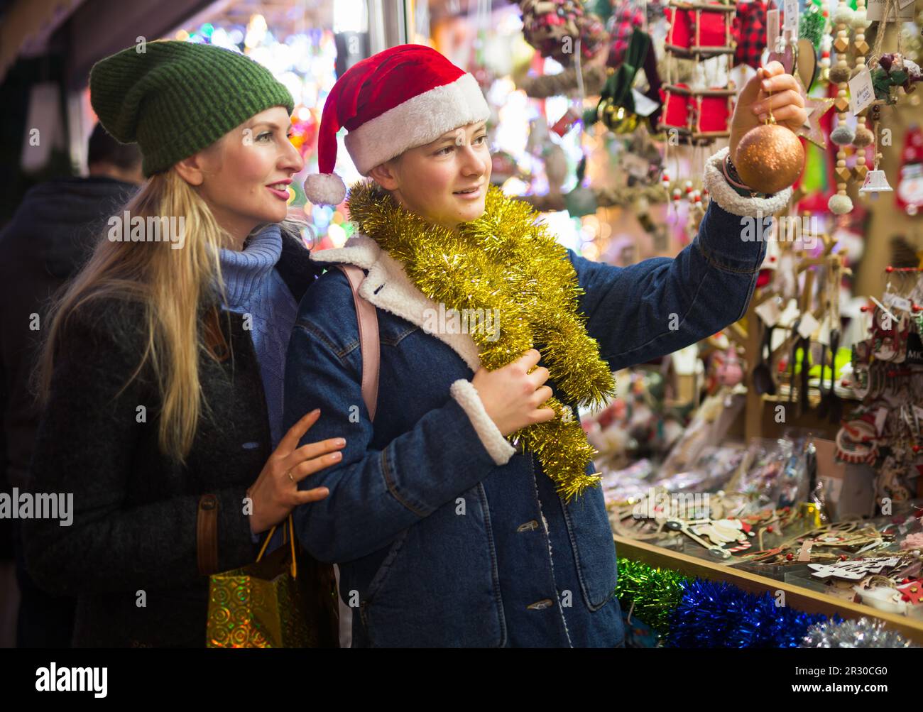 Girl and her mother purchasing decorations at christmas market Stock ...