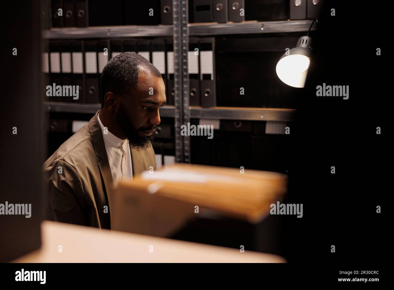 Concentrated african american cop working in police archive Stock Photo ...
