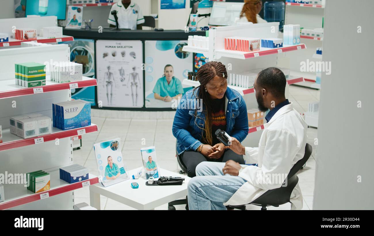 Young pharmacist giving bottle of drugs to customers Stock Photo - Alamy