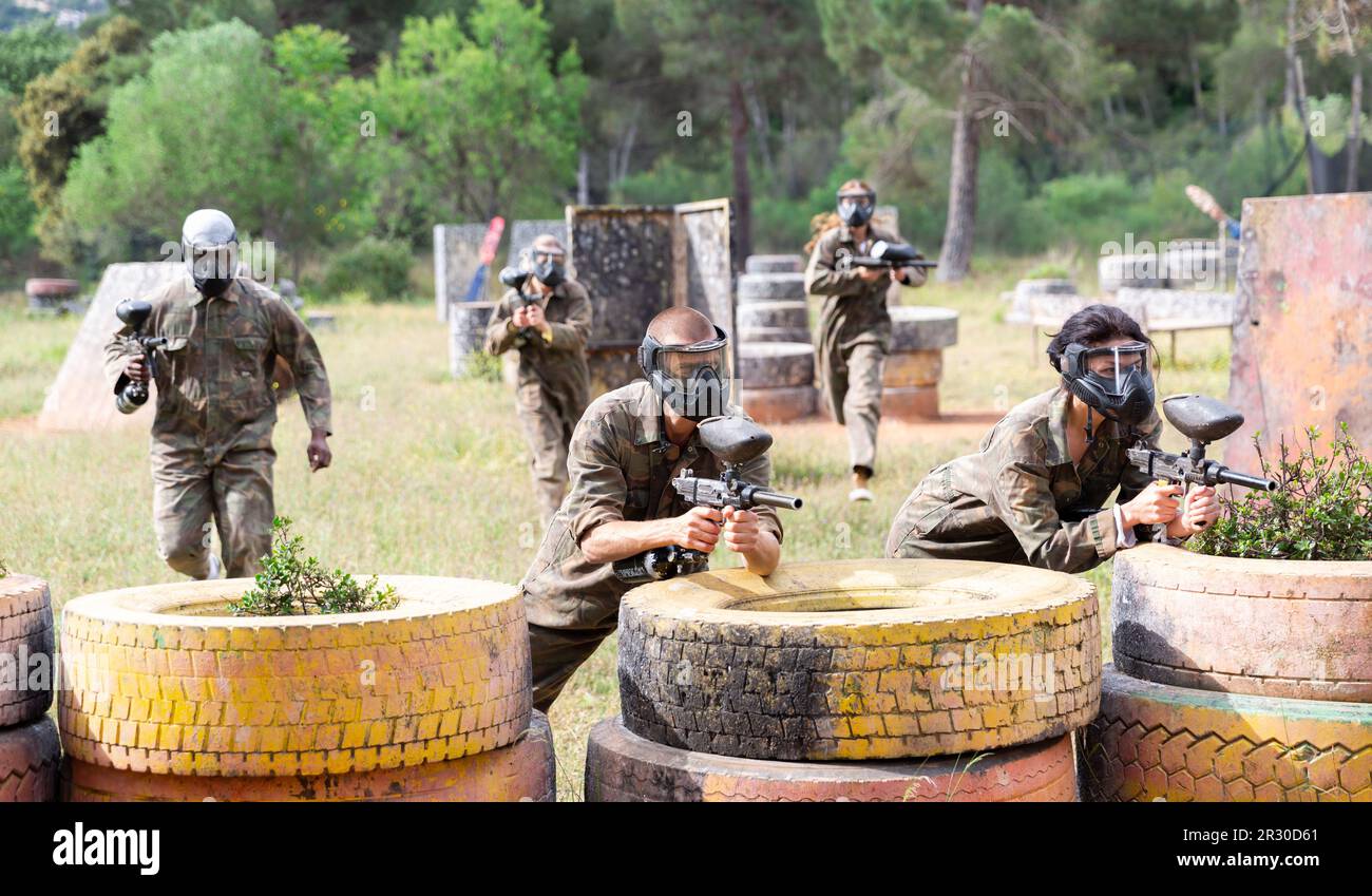 Expressive paintball team running with a marker guns at open playing ...