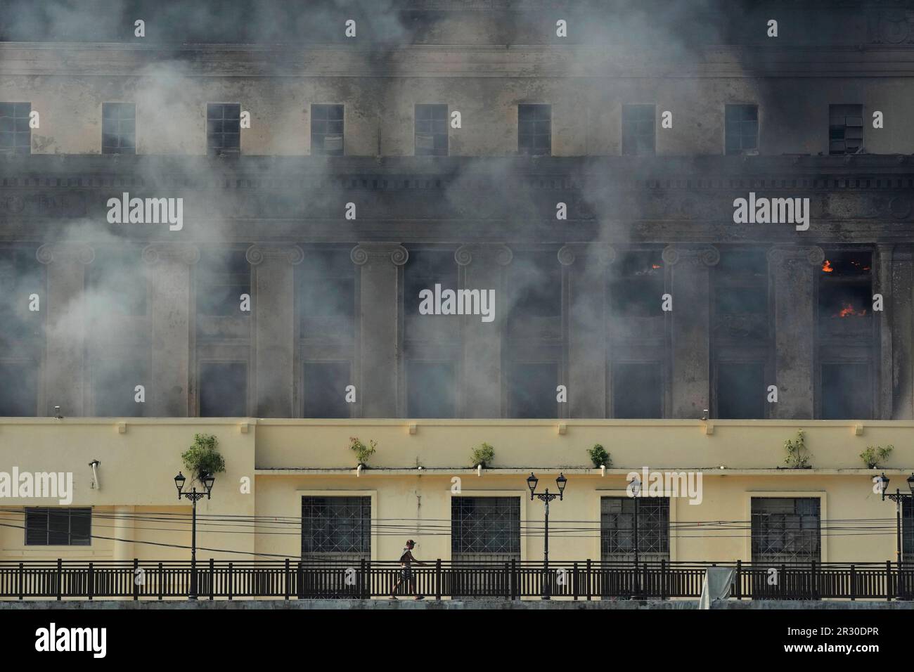 A man passes by the still smoldering Manila Central Post Office after ...