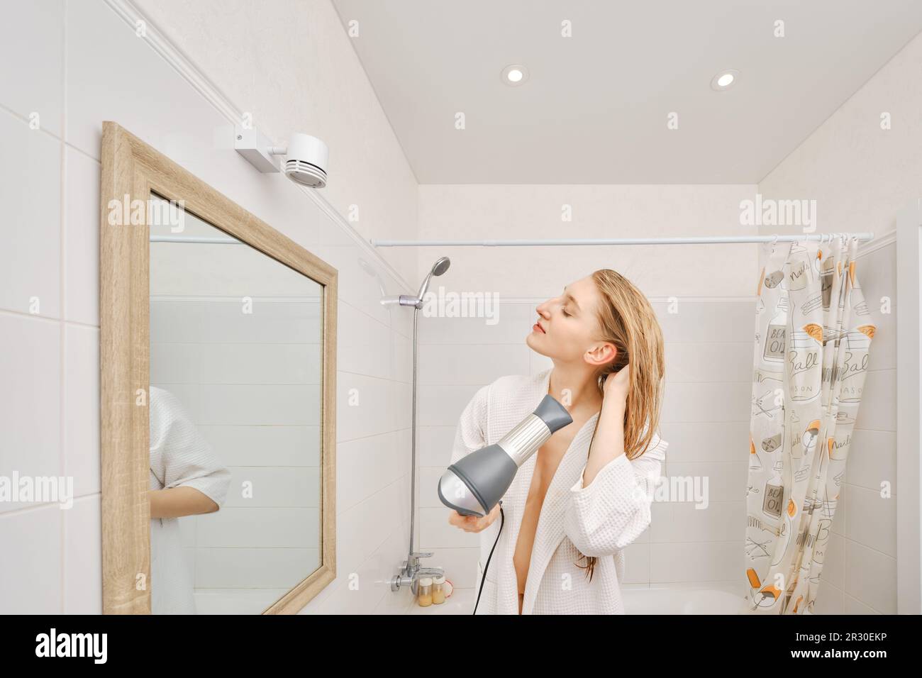 Beautiful woman drying her hair with a hair dryer in bathroom Stock ...