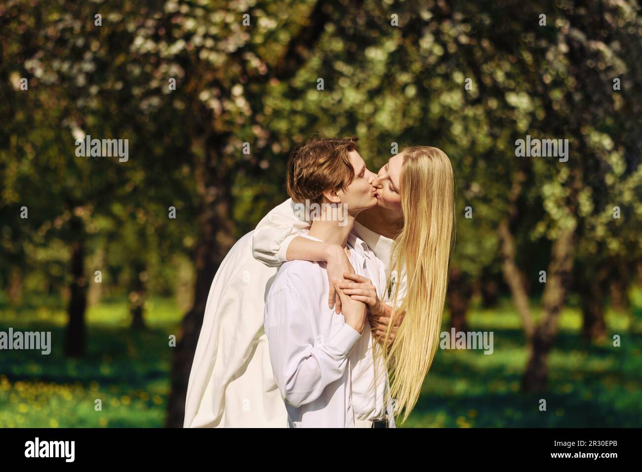 Blonde woman kissing her boyfriend outdoors Stock Photo - Alamy