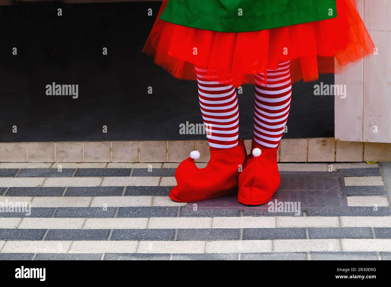 Red felt pointed shoes and striped stockings close up, Christmas elf ...