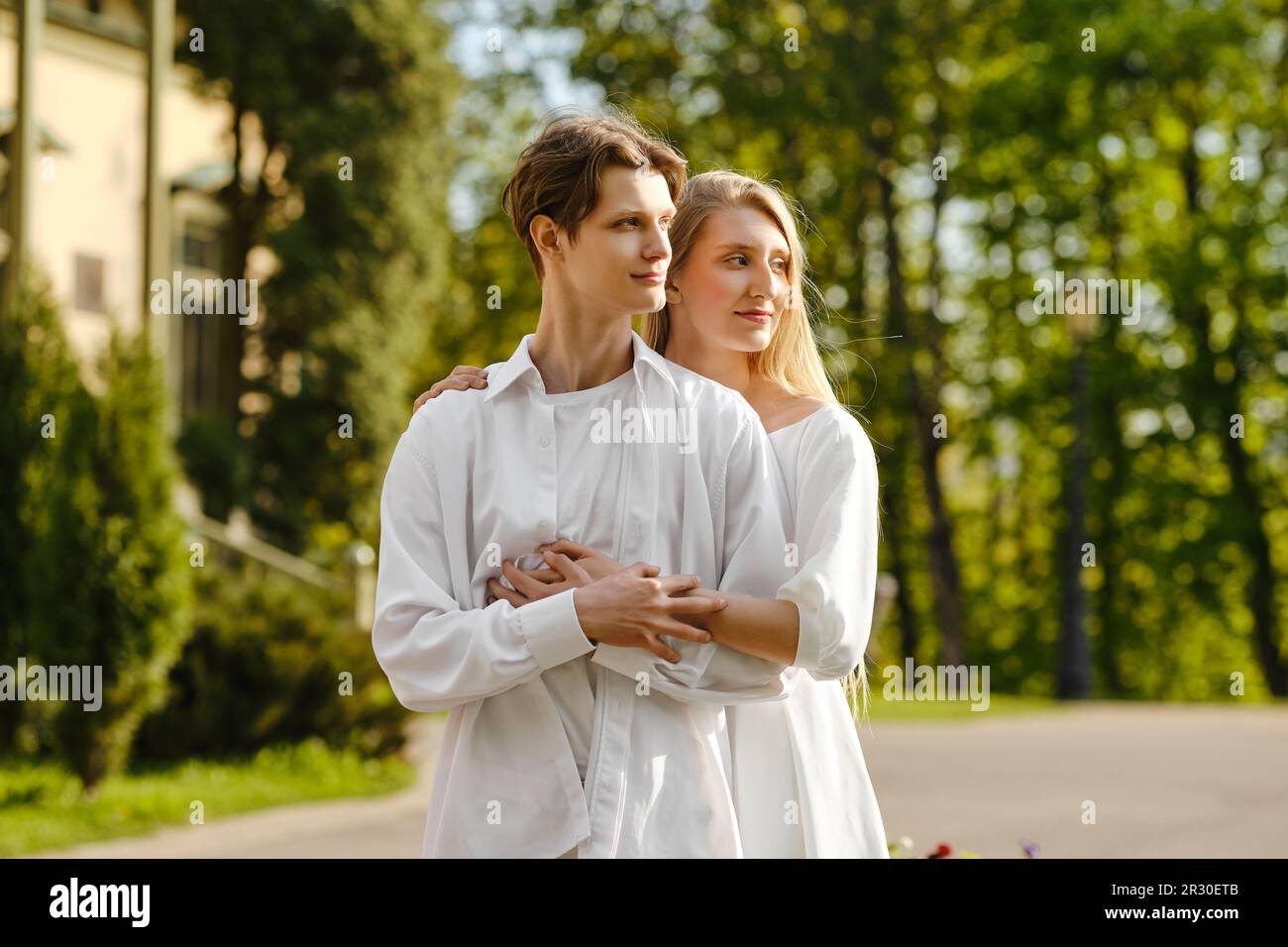 Happy couple in love hugging and looking to the side Stock Photo - Alamy