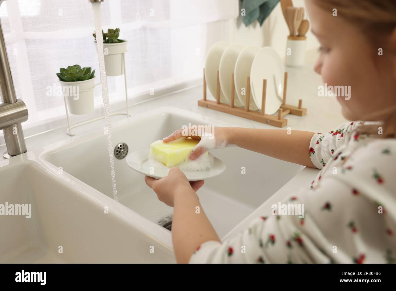 Little girl washing plate above sink indoors, closeup Stock Photo - Alamy