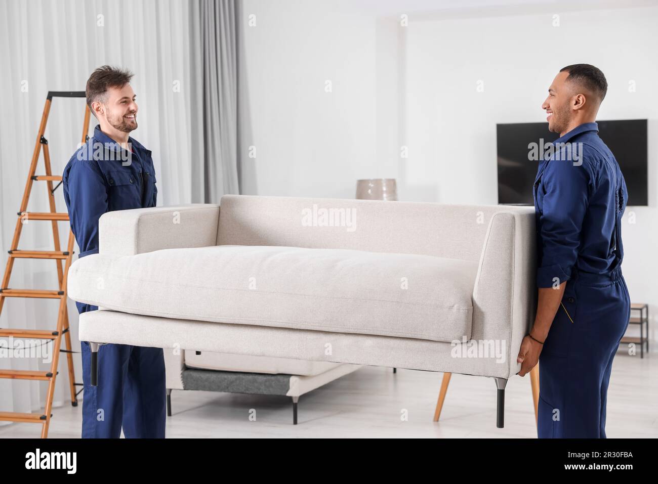 Male movers carrying sofa in new house Stock Photo - Alamy