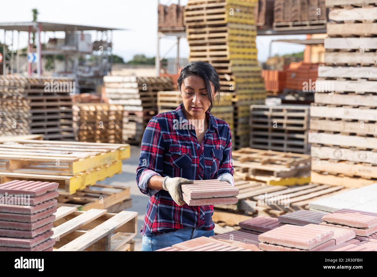 Woman places paving slabs on a pallet in building materials warehouse ...