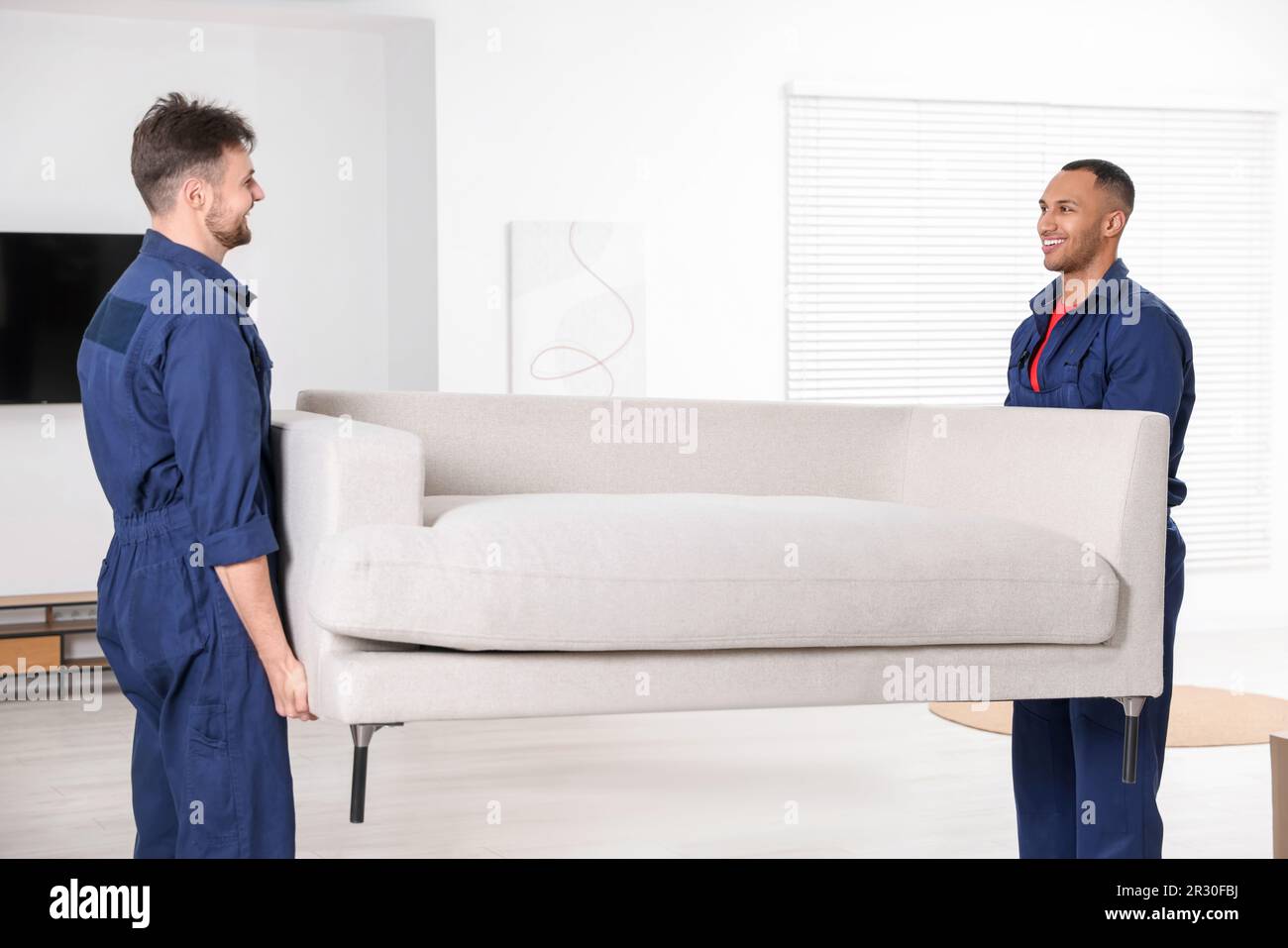 Male movers carrying sofa in new house Stock Photo - Alamy