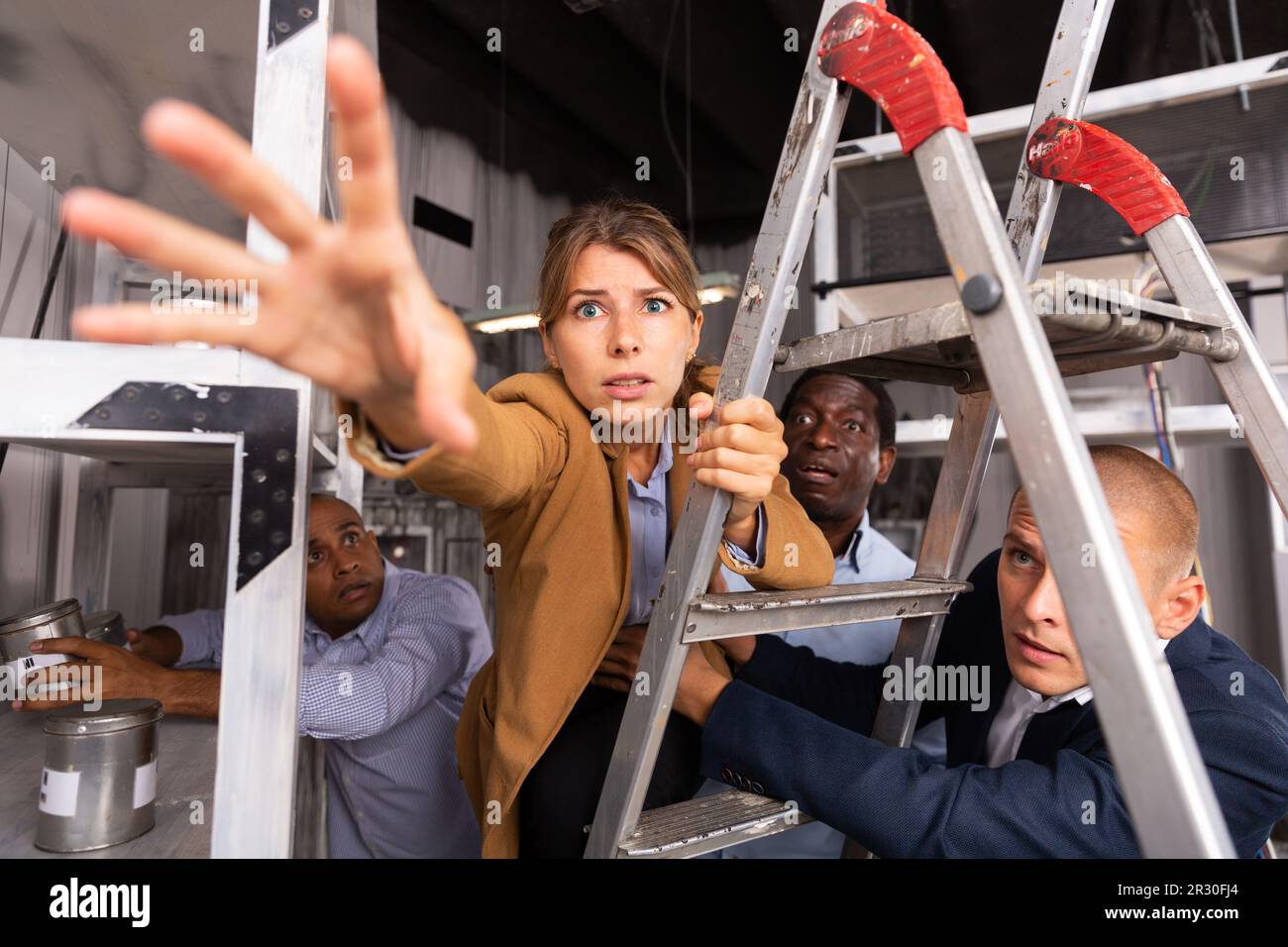 European girl on ladder in quest room with other multiracial people ...