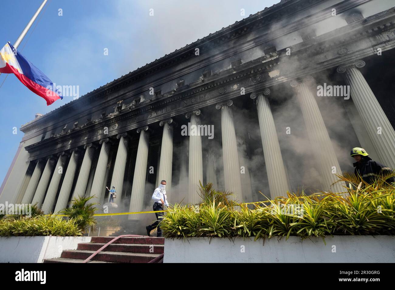 A security guard walks in front of the still smoldering Manila Central ...