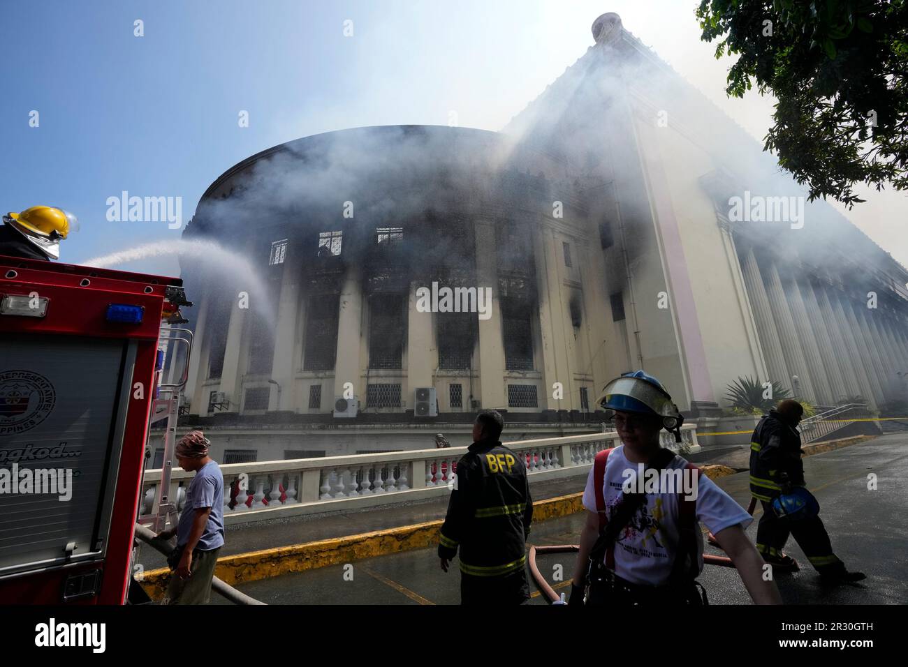 A fireman trains a hose outside the still smoldering Manila Central ...