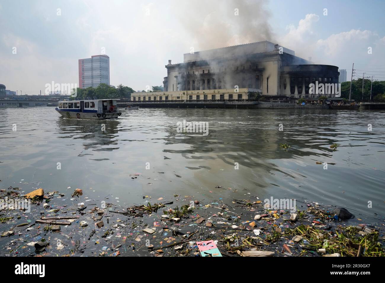A boat passes by the still smoldering Manila Central Post Office after ...