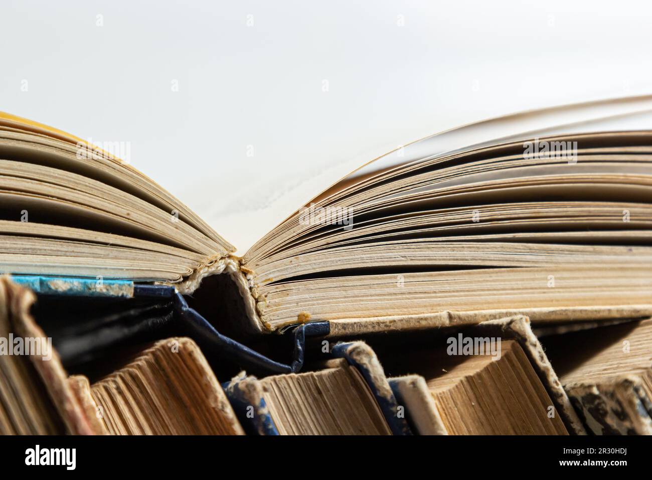 Stack of hardcover old books with an open book on white background ...
