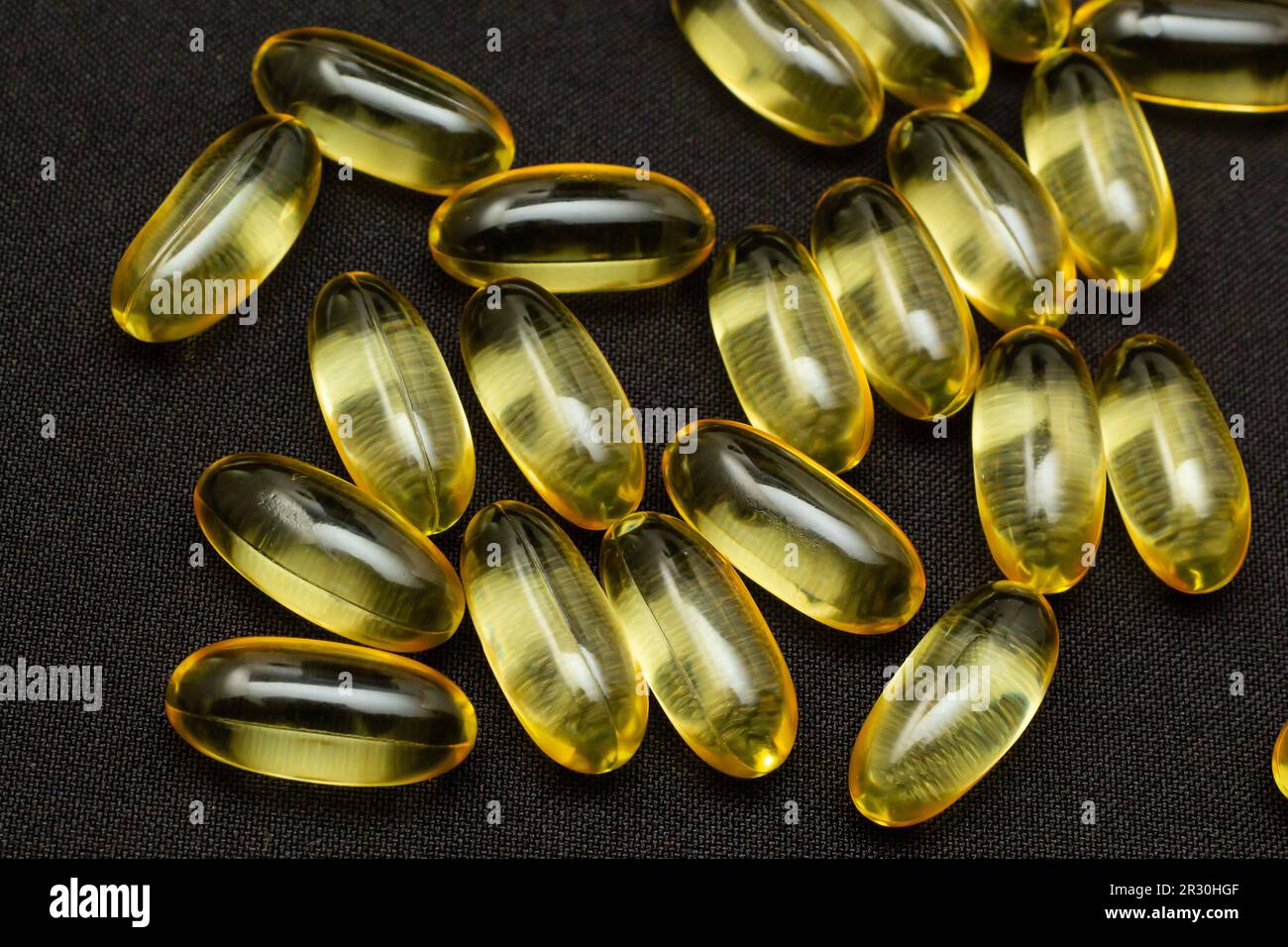 Macro Close up of Omega 3 gel capsule on a reflective black background ...
