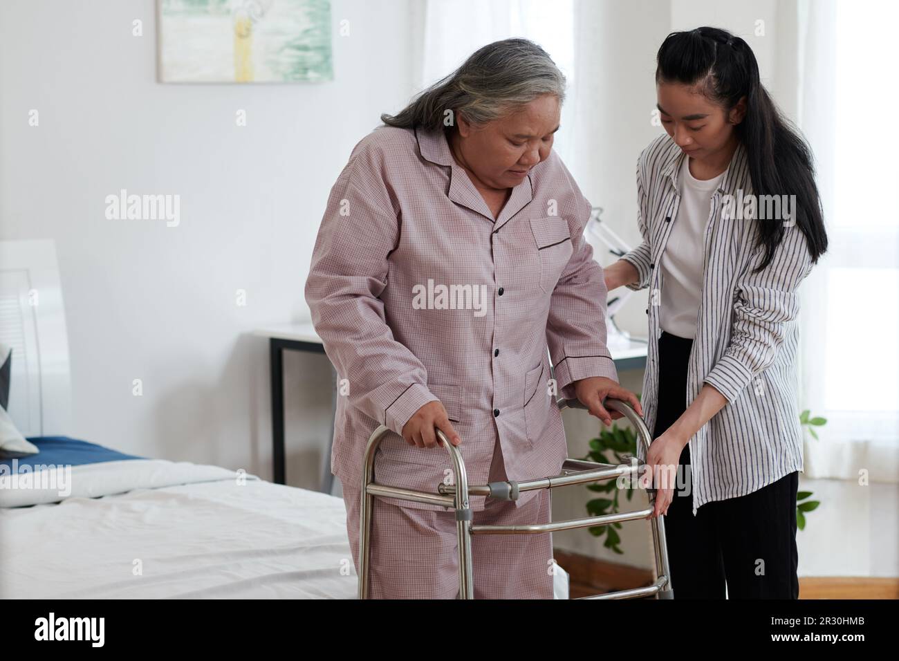 Senior woman using walker for the first time under control of her adult ...