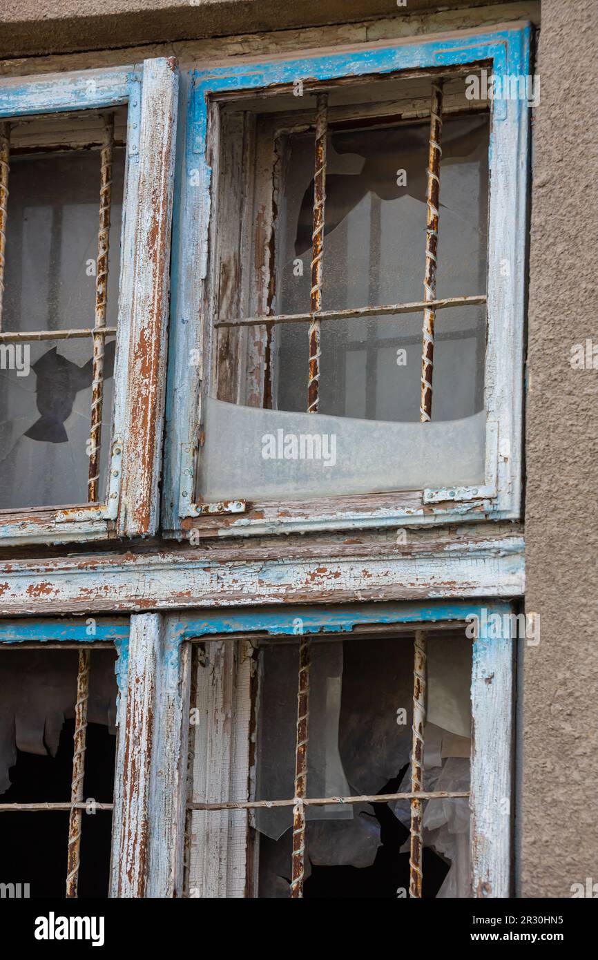 Old window with worn wooden shutters and broken glass on exterior wall ...