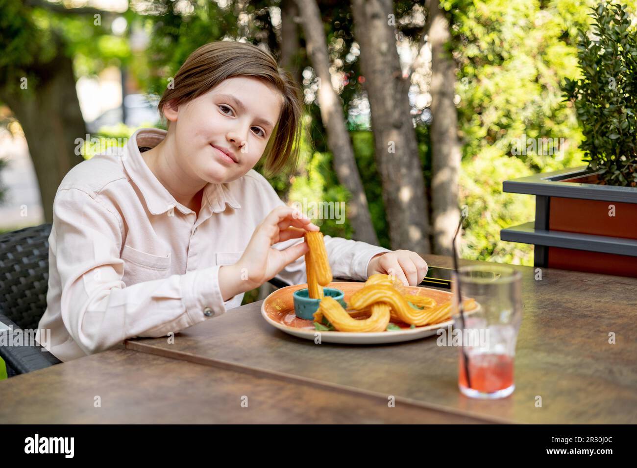 Portrait of teenager boy eating french churros in the outdoor summer ...