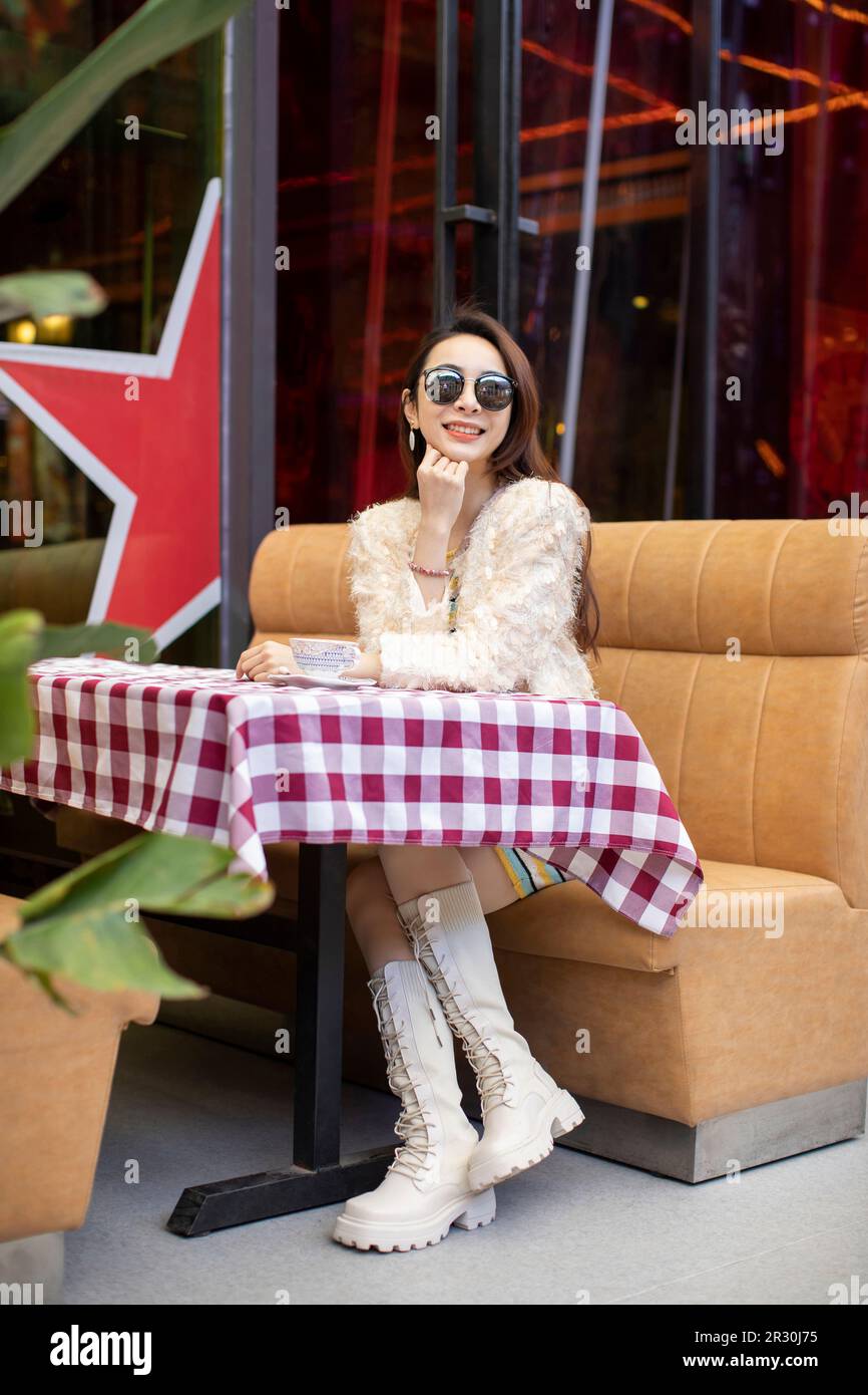 Cheerful young Chinese woman drinking coffee in café Stock Photo - Alamy