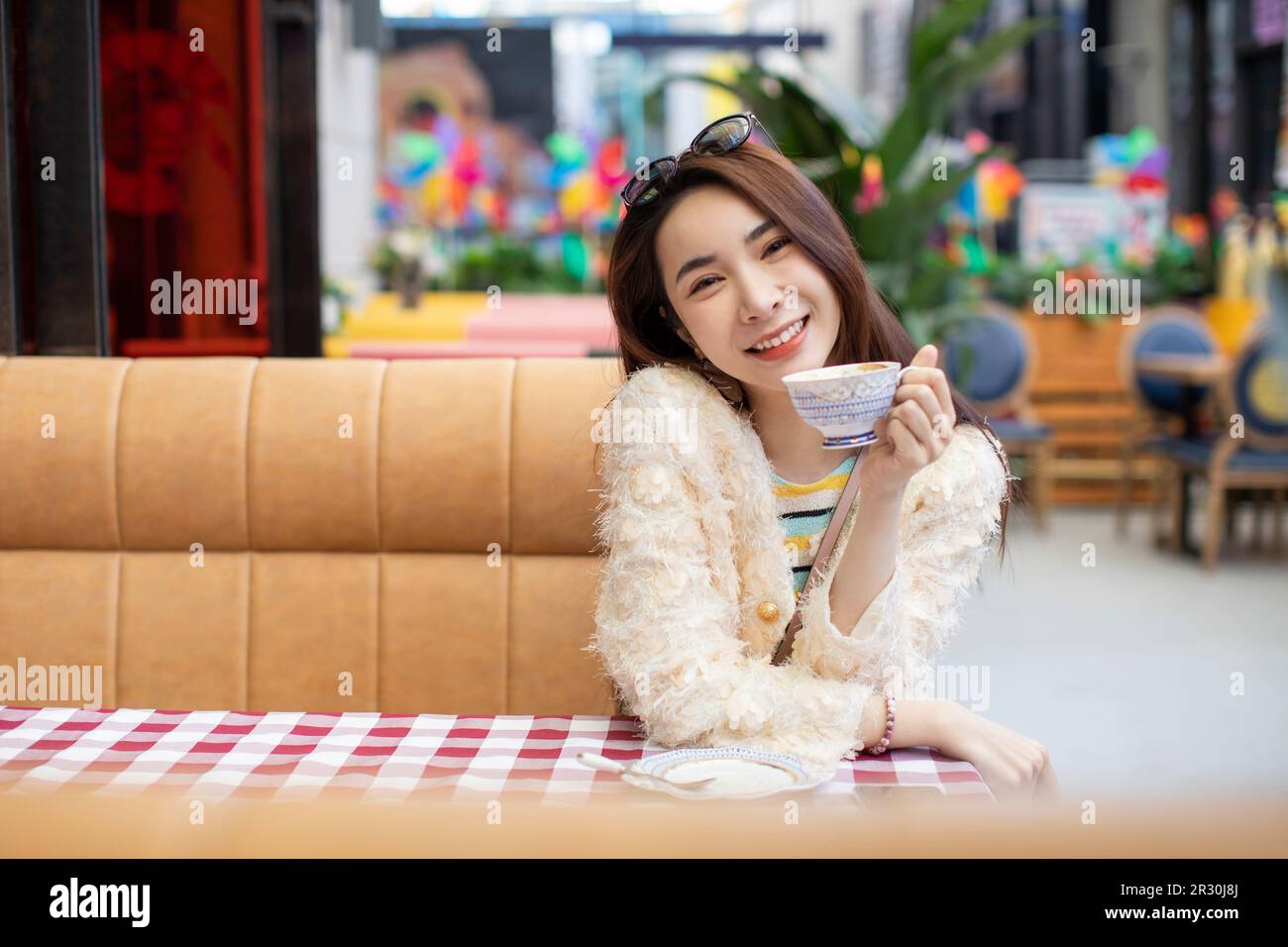 Cheerful young Chinese woman drinking coffee in café Stock Photo - Alamy