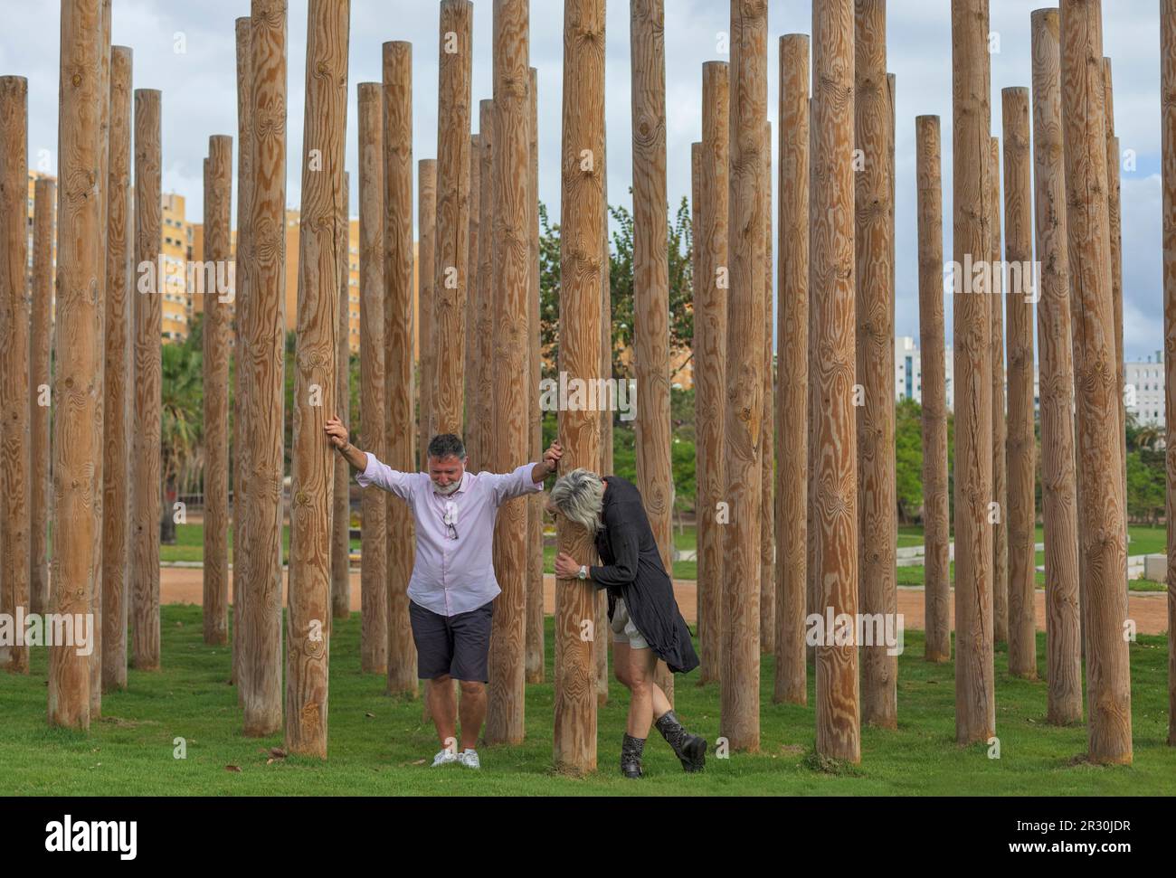 A middle-aged couple plays between decorative wooden poles in a garden ...