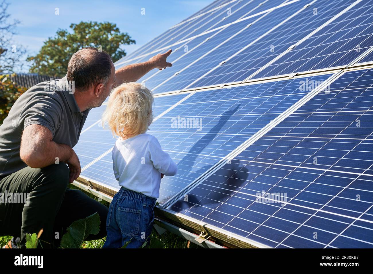 Man showing his small child the solar panels during sunny day. Father ...