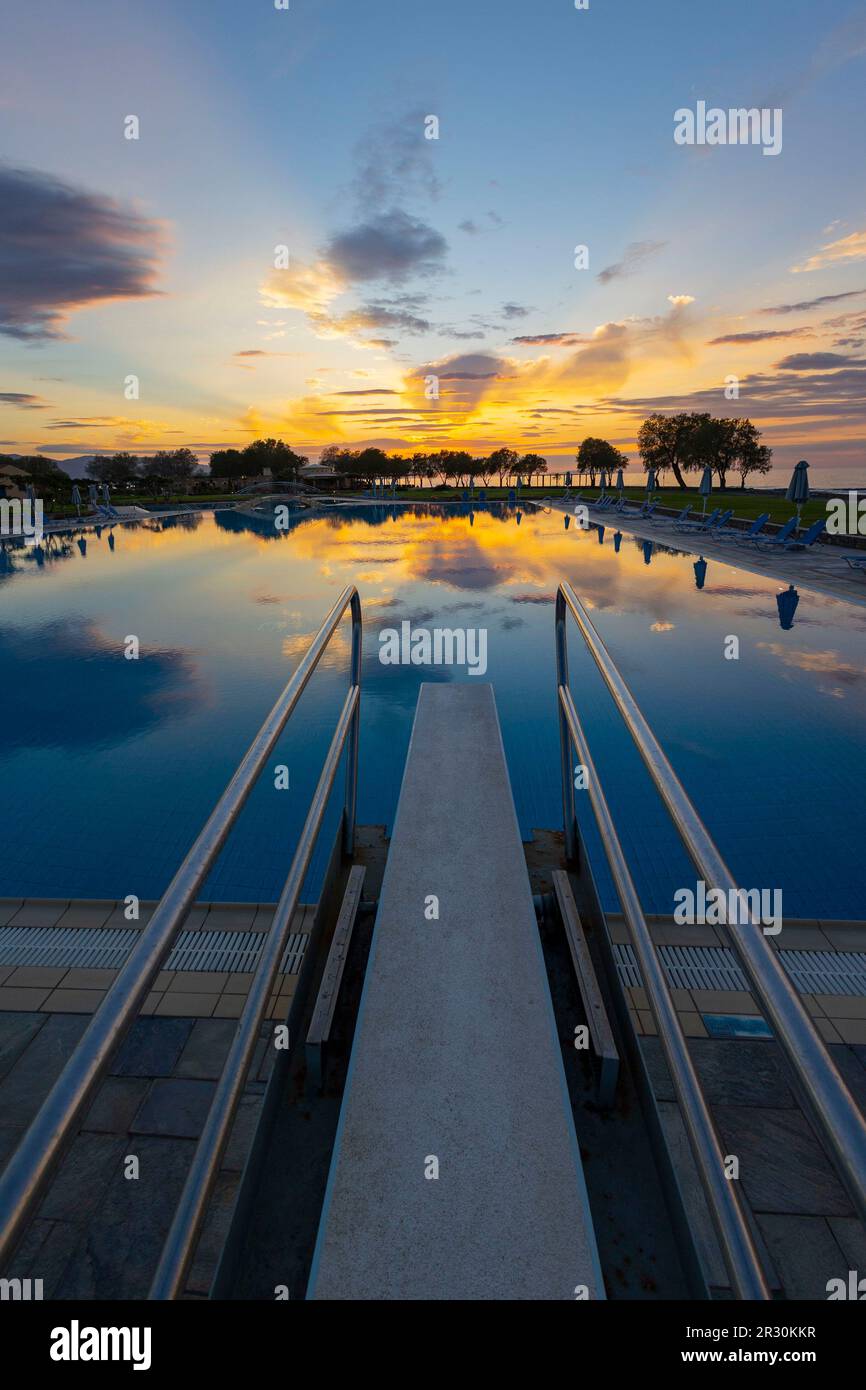 Outdoor swimming pool in Kalimera Kriti resort at sunset time with ...