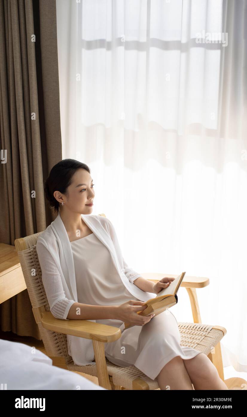Elegant young Chinese woman reading book at home Stock Photo - Alamy