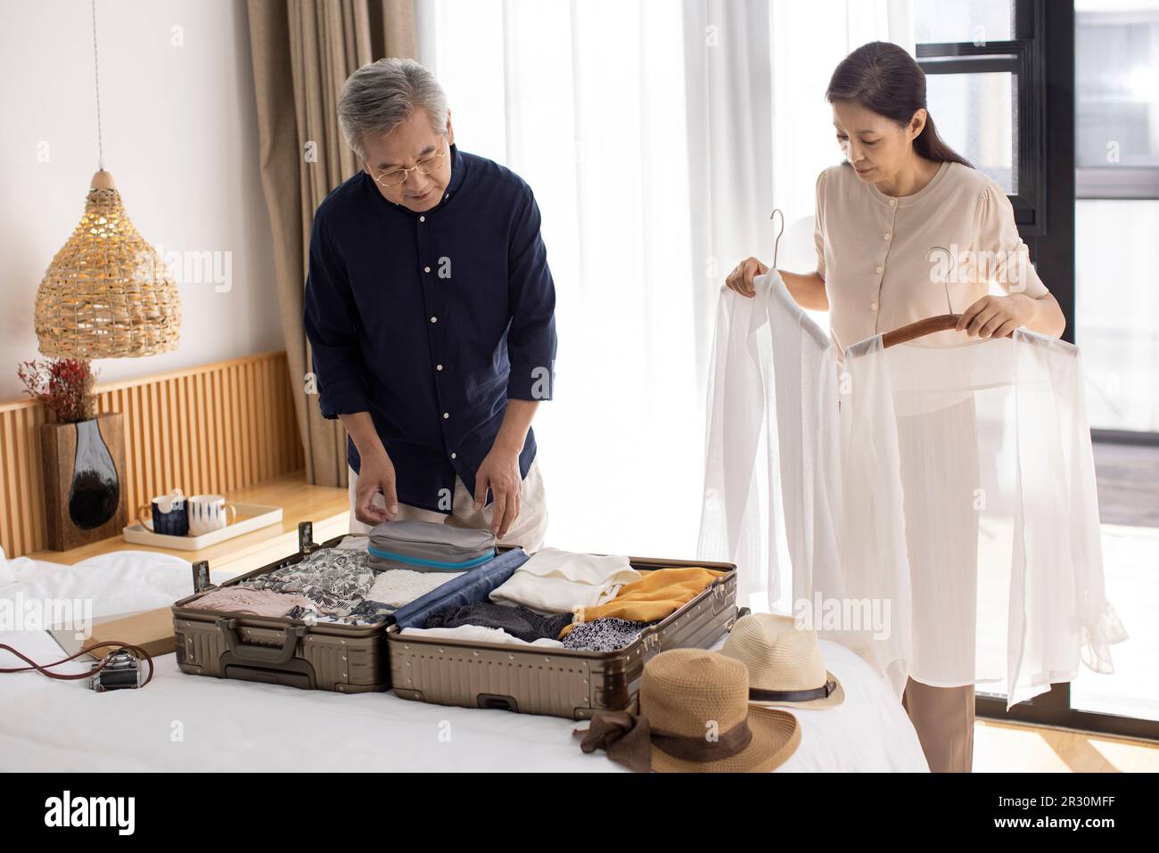 Happy mature Chinese couple packing suitcase for vacation Stock Photo ...
