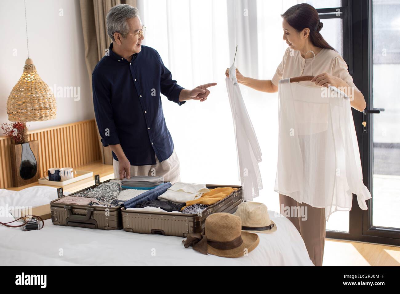 Happy mature Chinese couple packing suitcase for vacation Stock Photo ...