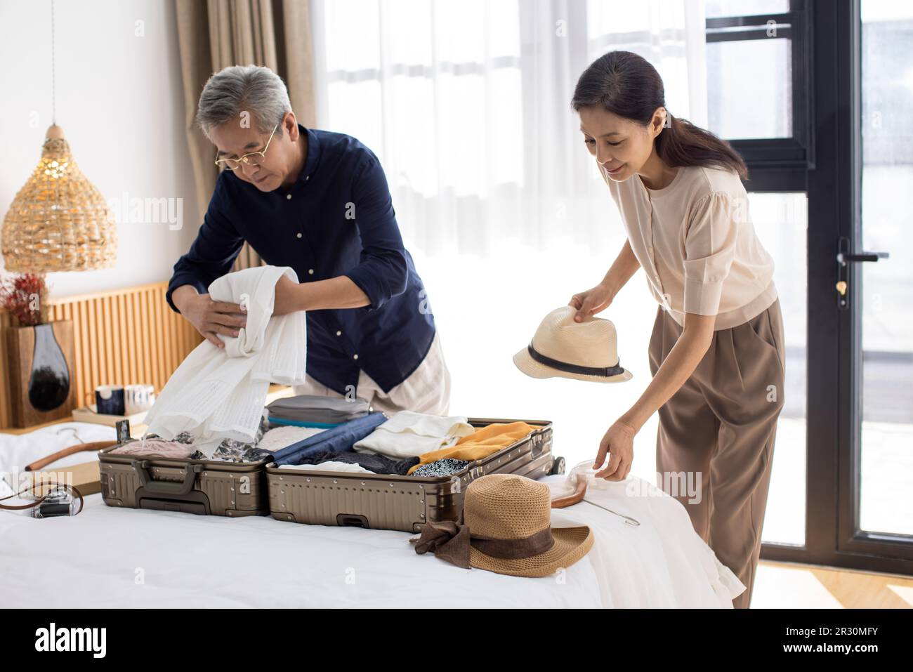 Happy mature Chinese couple packing suitcase for vacation Stock Photo ...