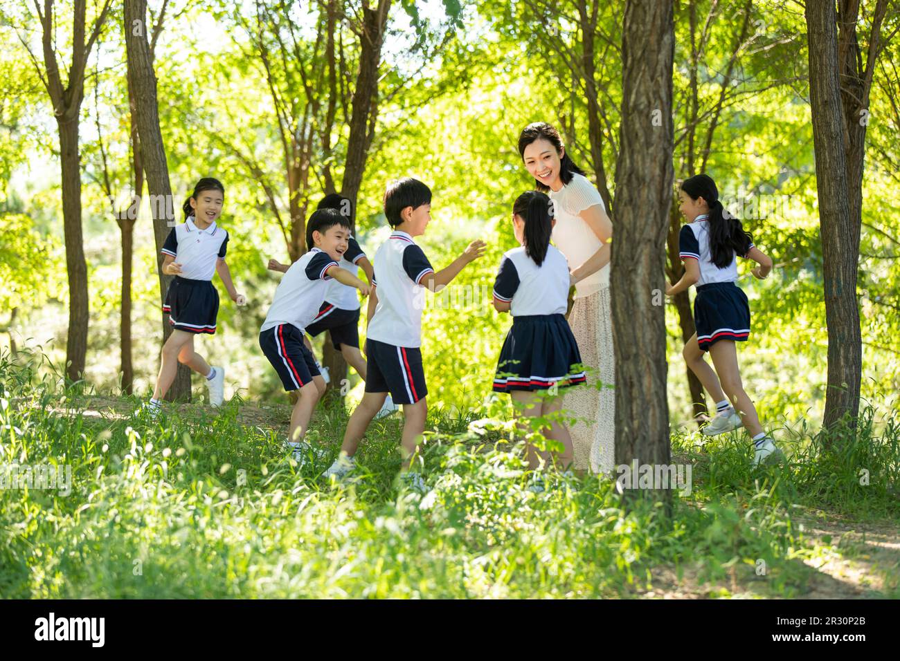 Cheerful Chinese school children relaxing in park with their teacher Stock Photo - Alamy