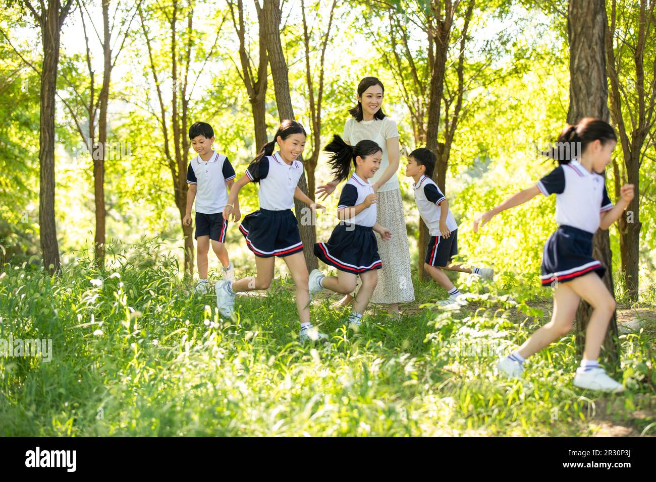 Cheerful Chinese school children relaxing in park with their teacher Stock Photo - Alamy