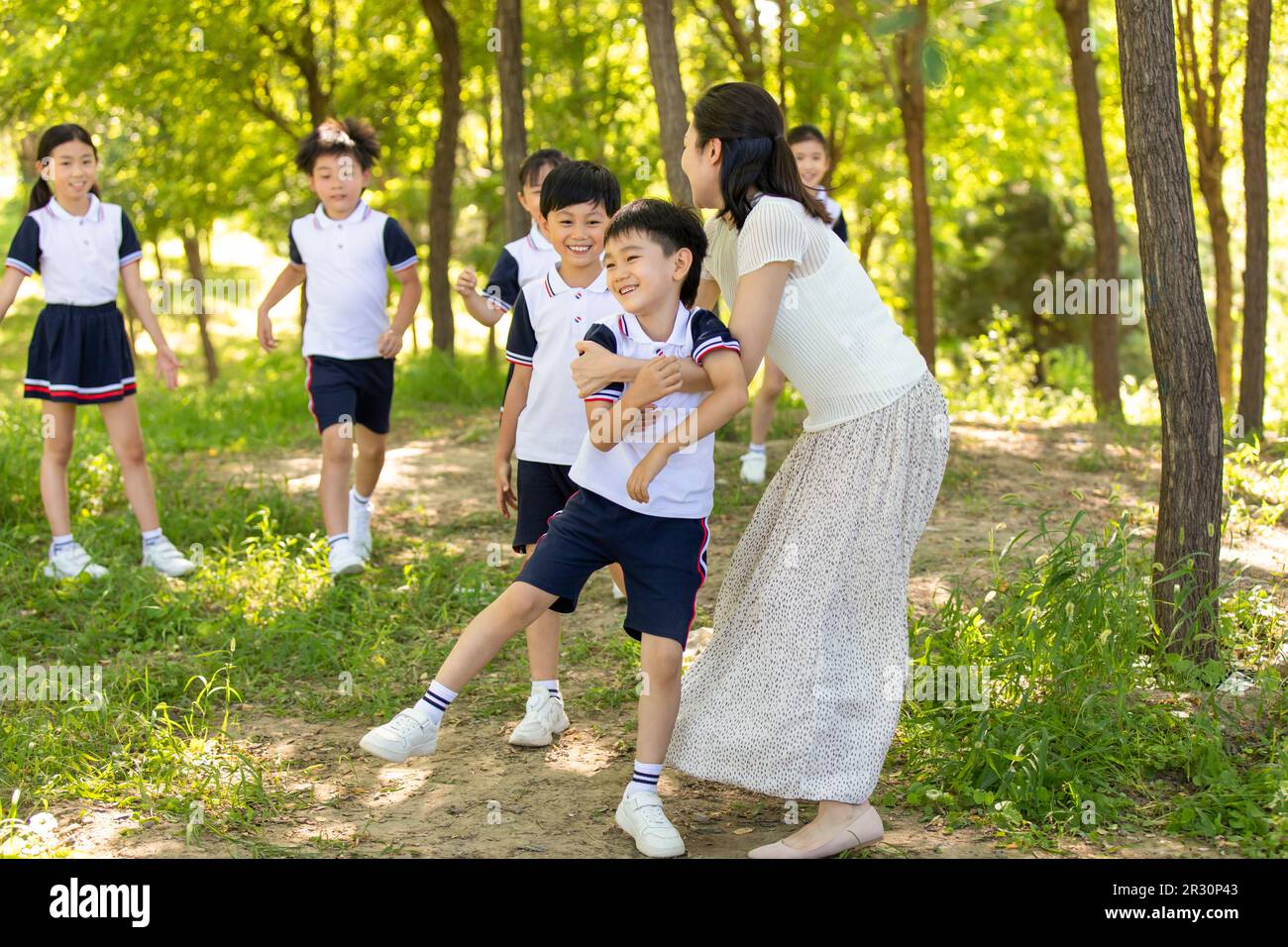 Cheerful Chinese school children relaxing in park with their teacher Stock Photo - Alamy