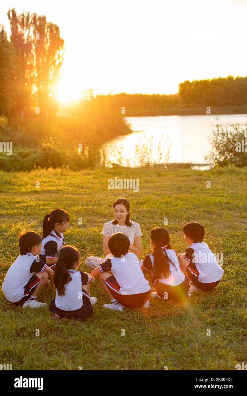 Cheerful Chinese school children relaxing in park with their teacher Stock Photo - Alamy