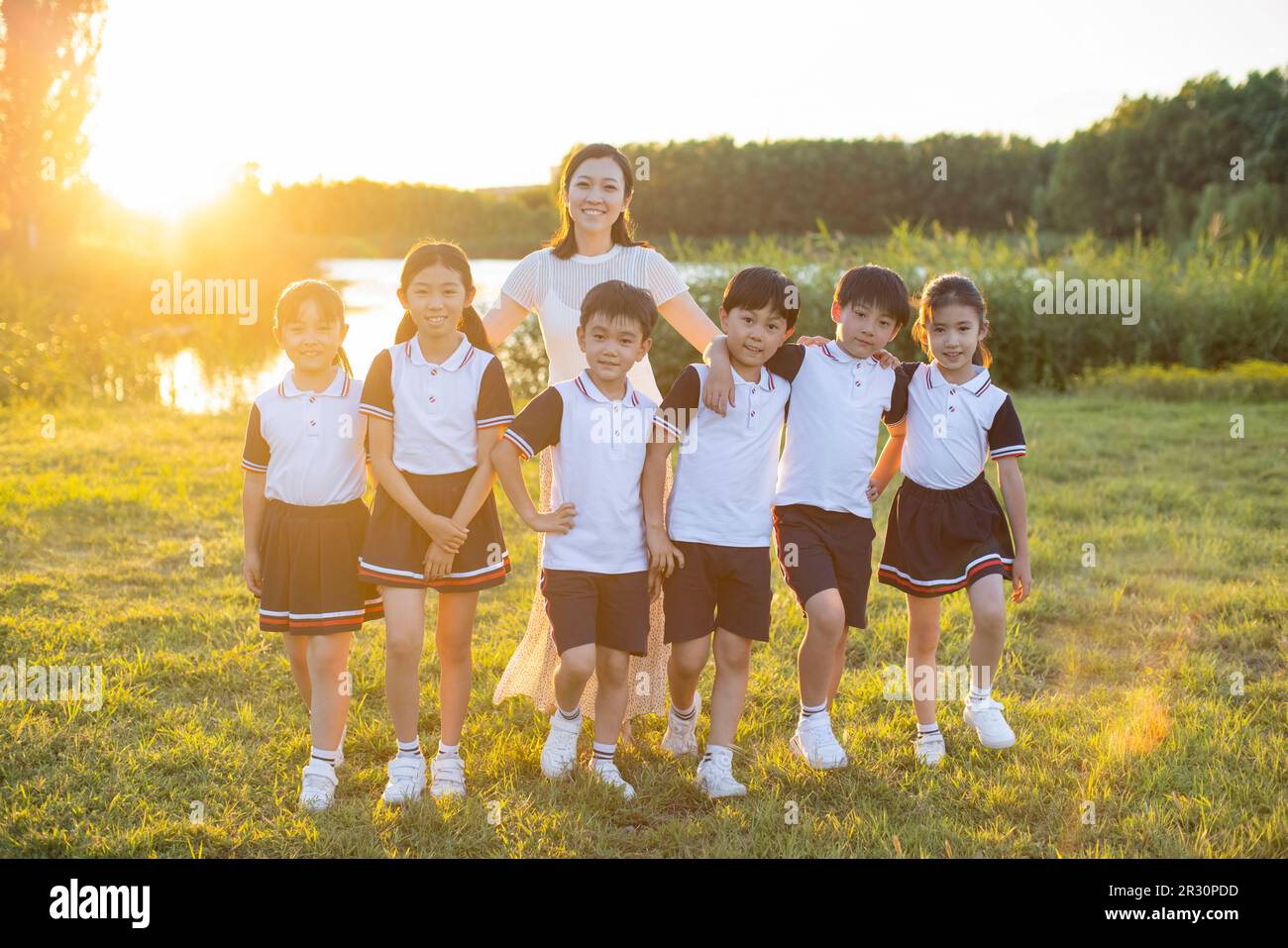 Cheerful Chinese school children relaxing in park with their teacher Stock Photo - Alamy