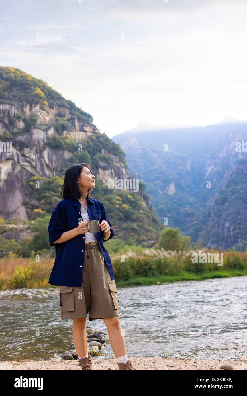 Cheerful young Chinese woman enjoying the beautiful natural scenery ...