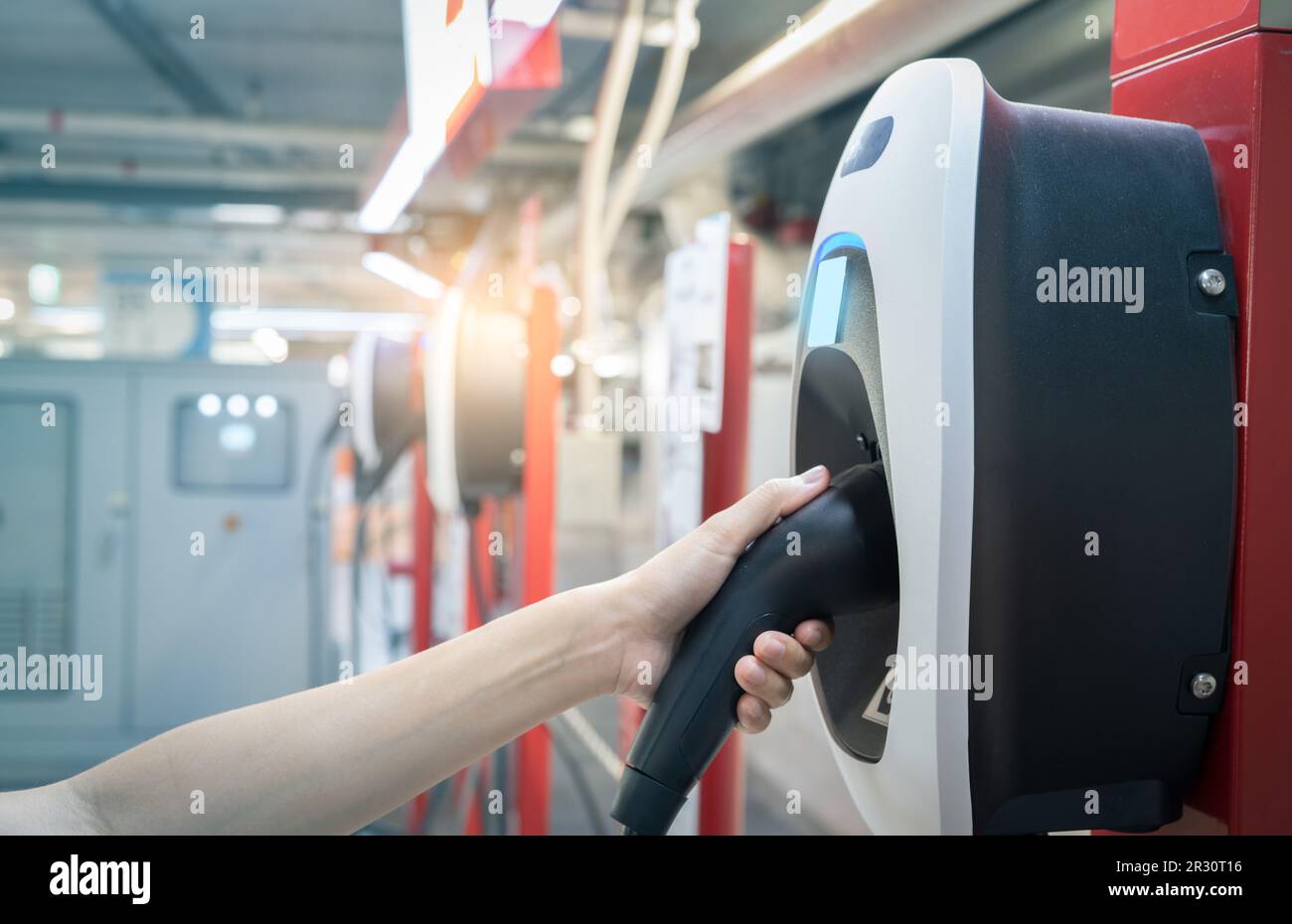 Hand holding electric plug-in charger at electric vehicle charging ...