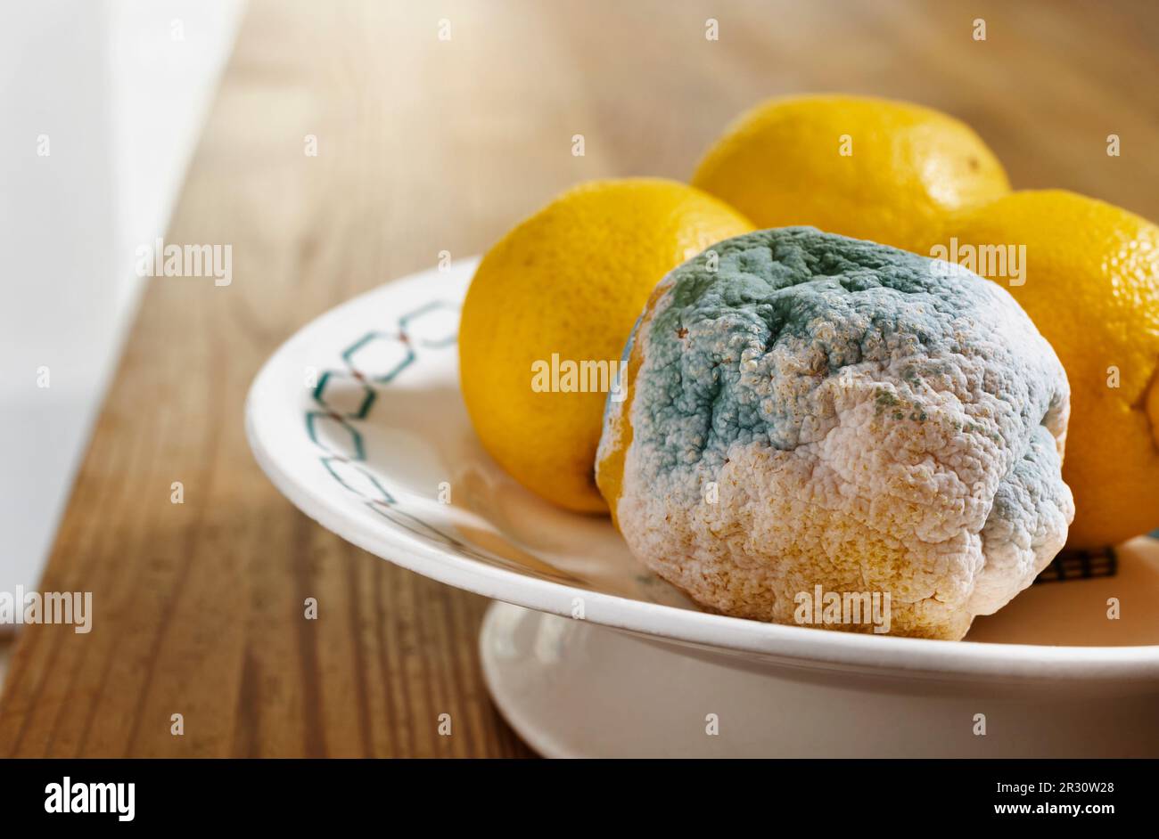 Plate on wooden table with rotten lemon and fresh fruit Stock Photo - Alamy