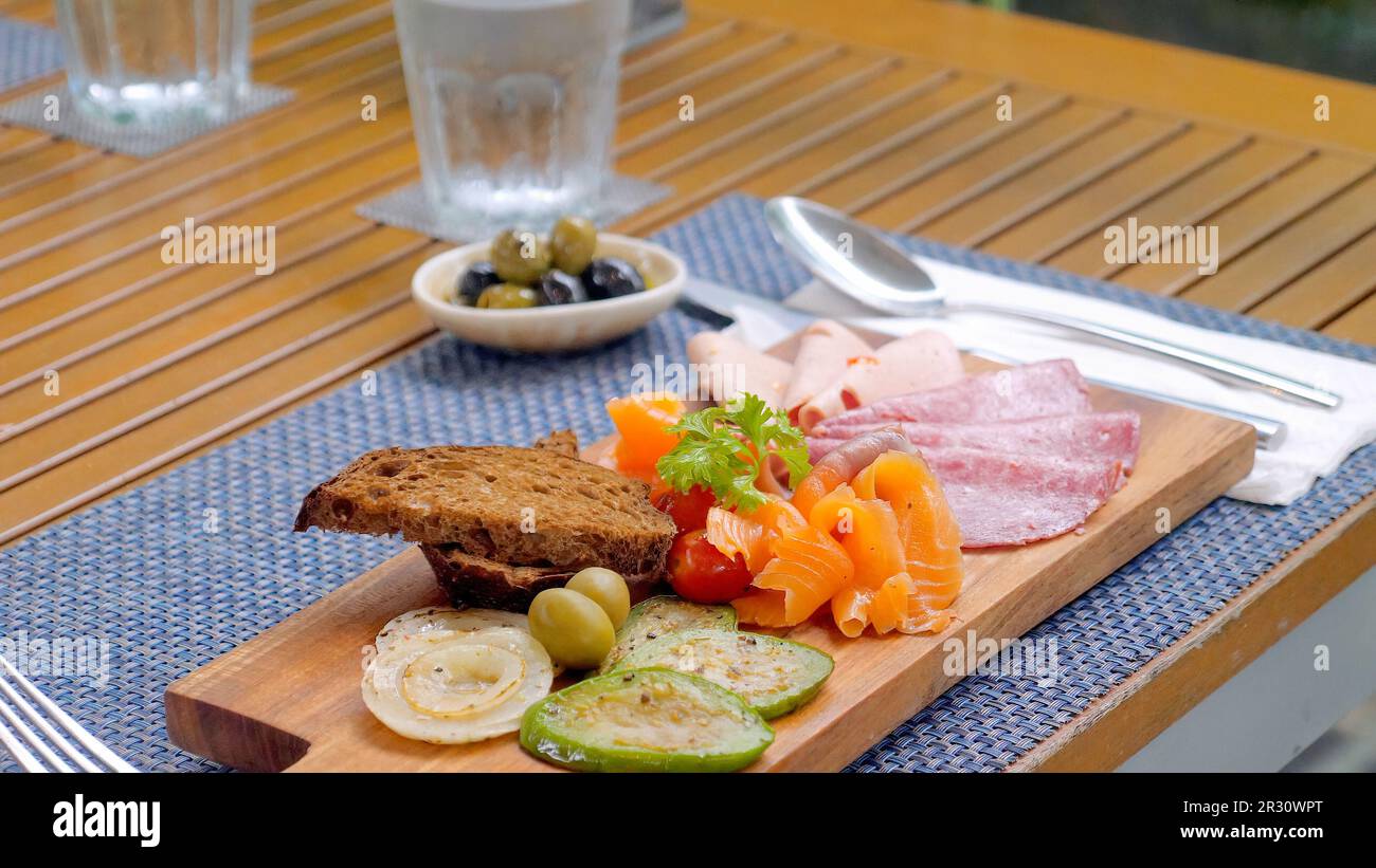 Wooden cutting board with meat and vegetables, cold cuts in restaurant ...