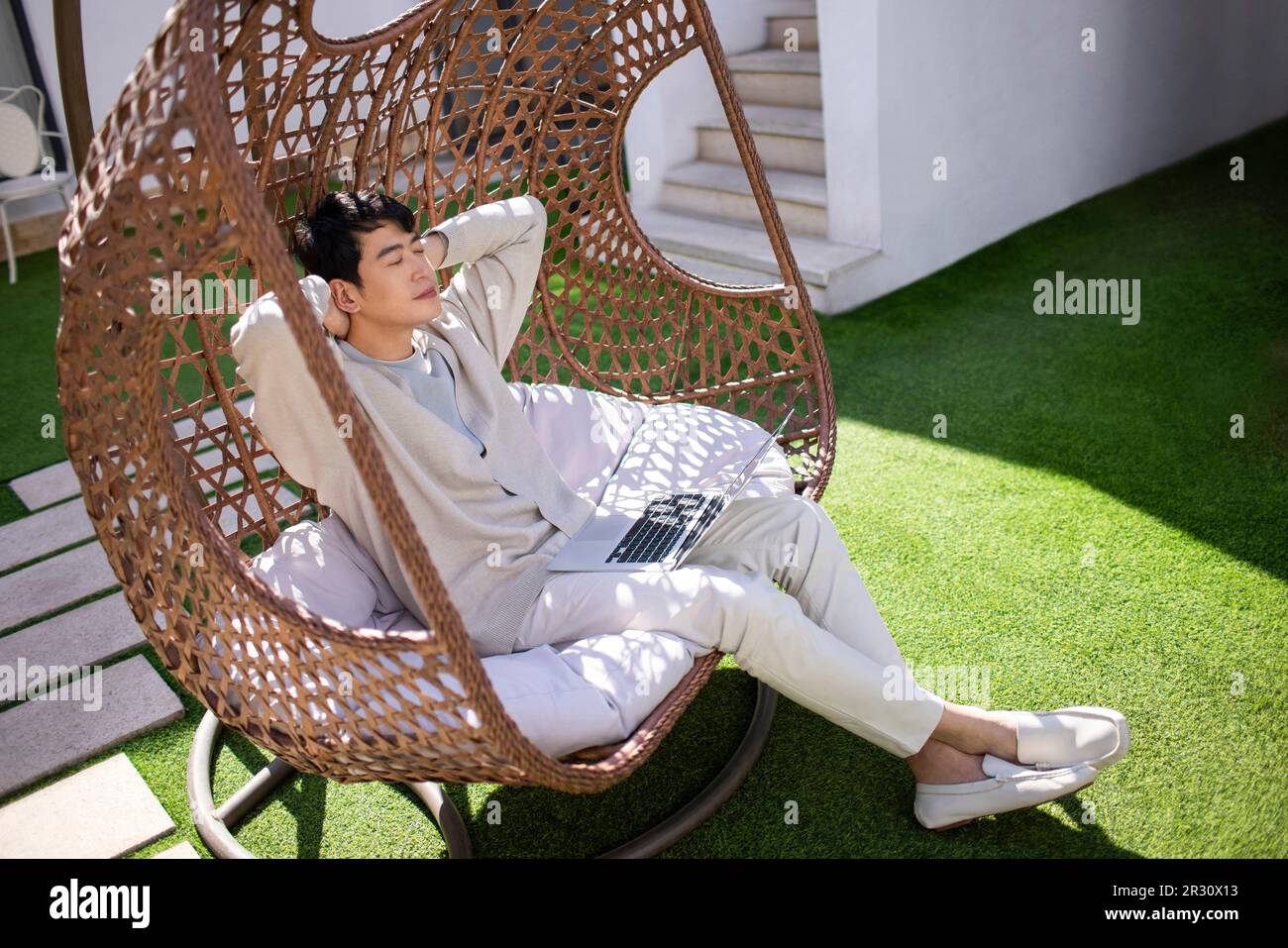 Happy mid adult Chinese man relaxing on hanging-chair Stock Photo - Alamy