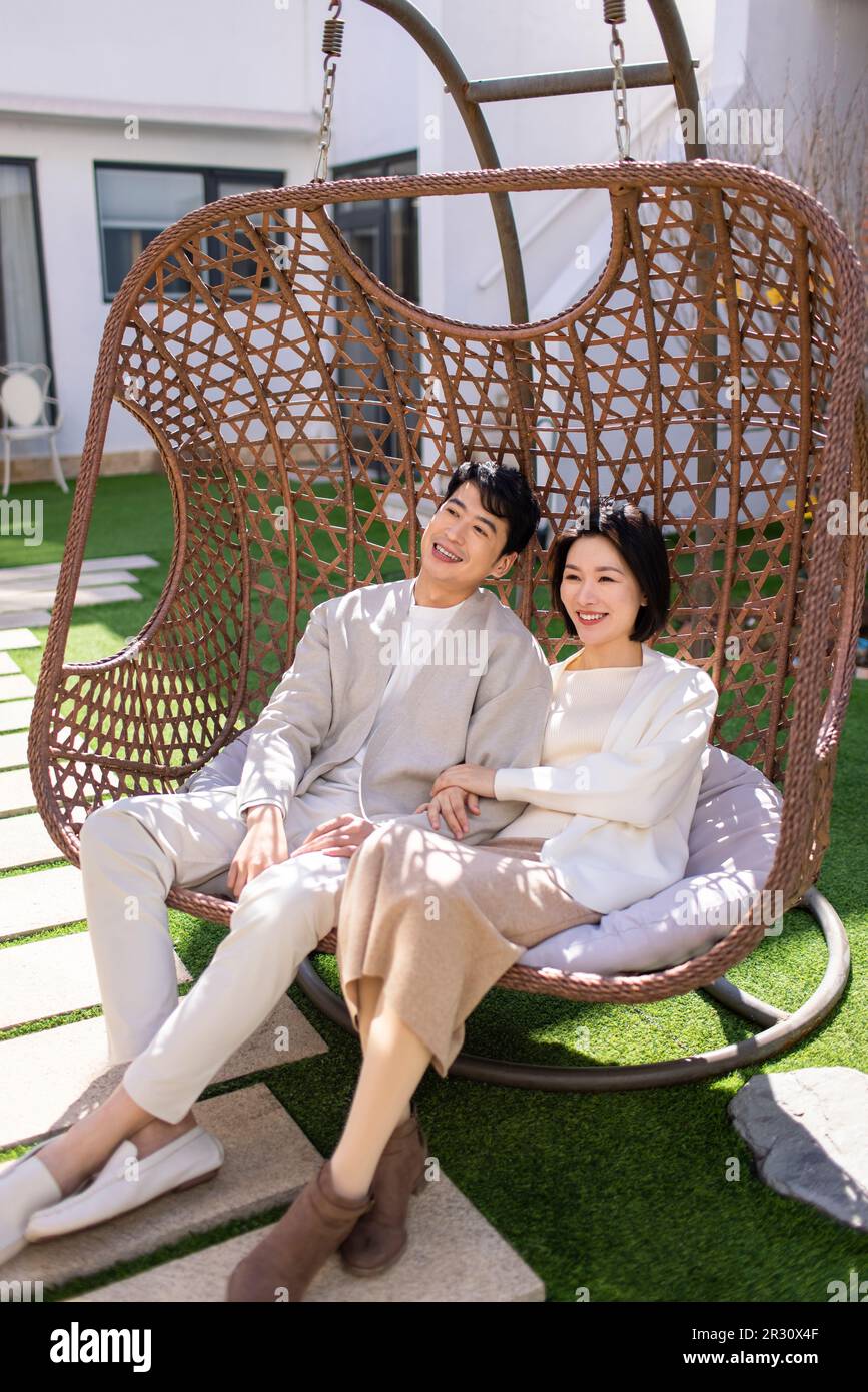 Happy young Chinese couple relaxing on hanging-chair Stock Photo - Alamy