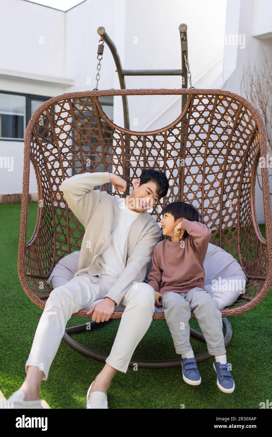 Happy little Chinese boy with his father on hanging-chair Stock Photo ...