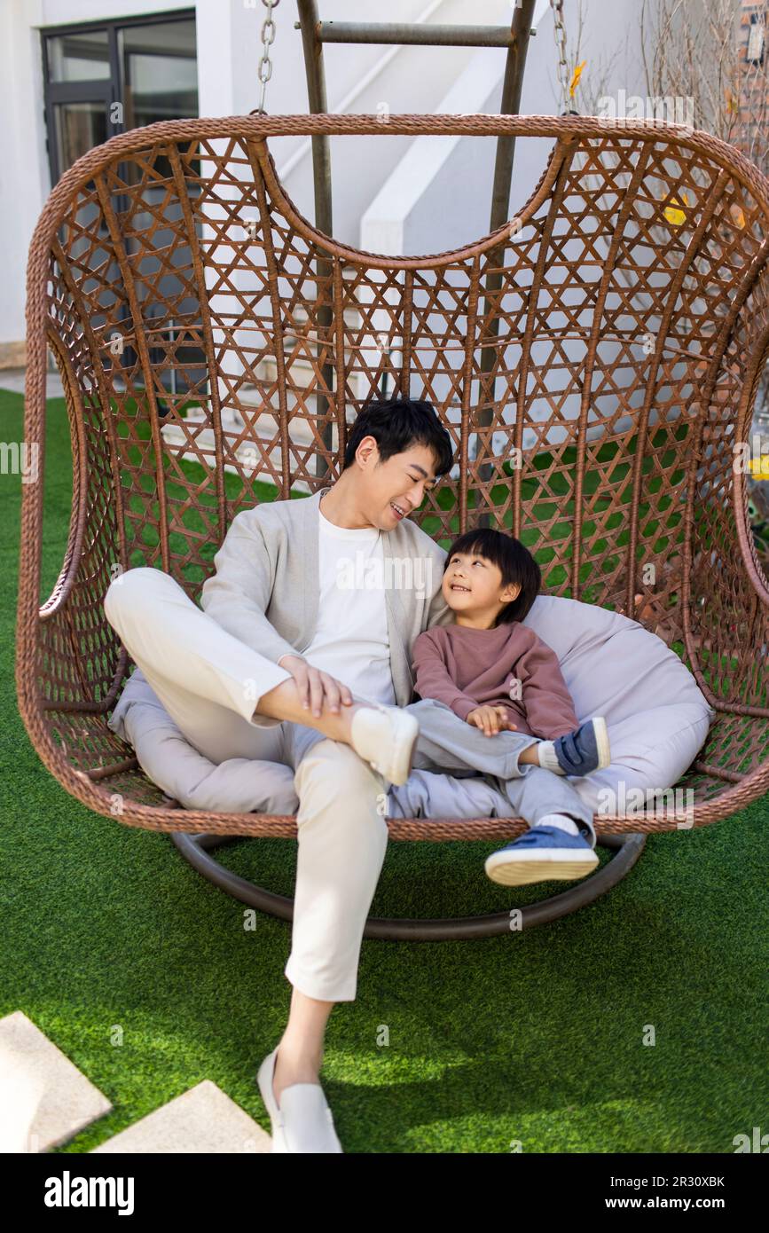 Happy little Chinese boy with his father on hanging-chair Stock Photo ...