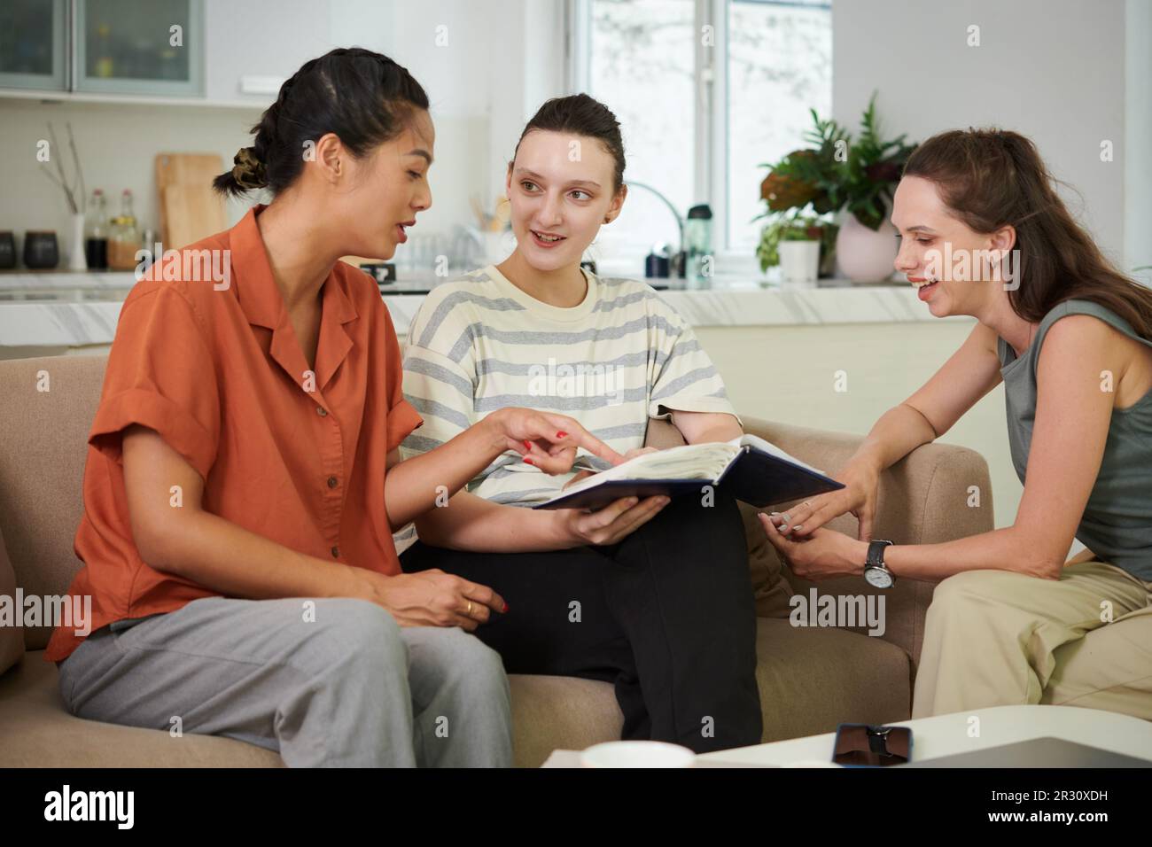 Friends gathering at home to discuss old photos in album Stock Photo ...