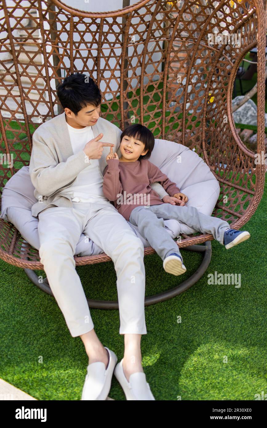 Happy little Chinese boy with his father on hanging-chair Stock Photo ...