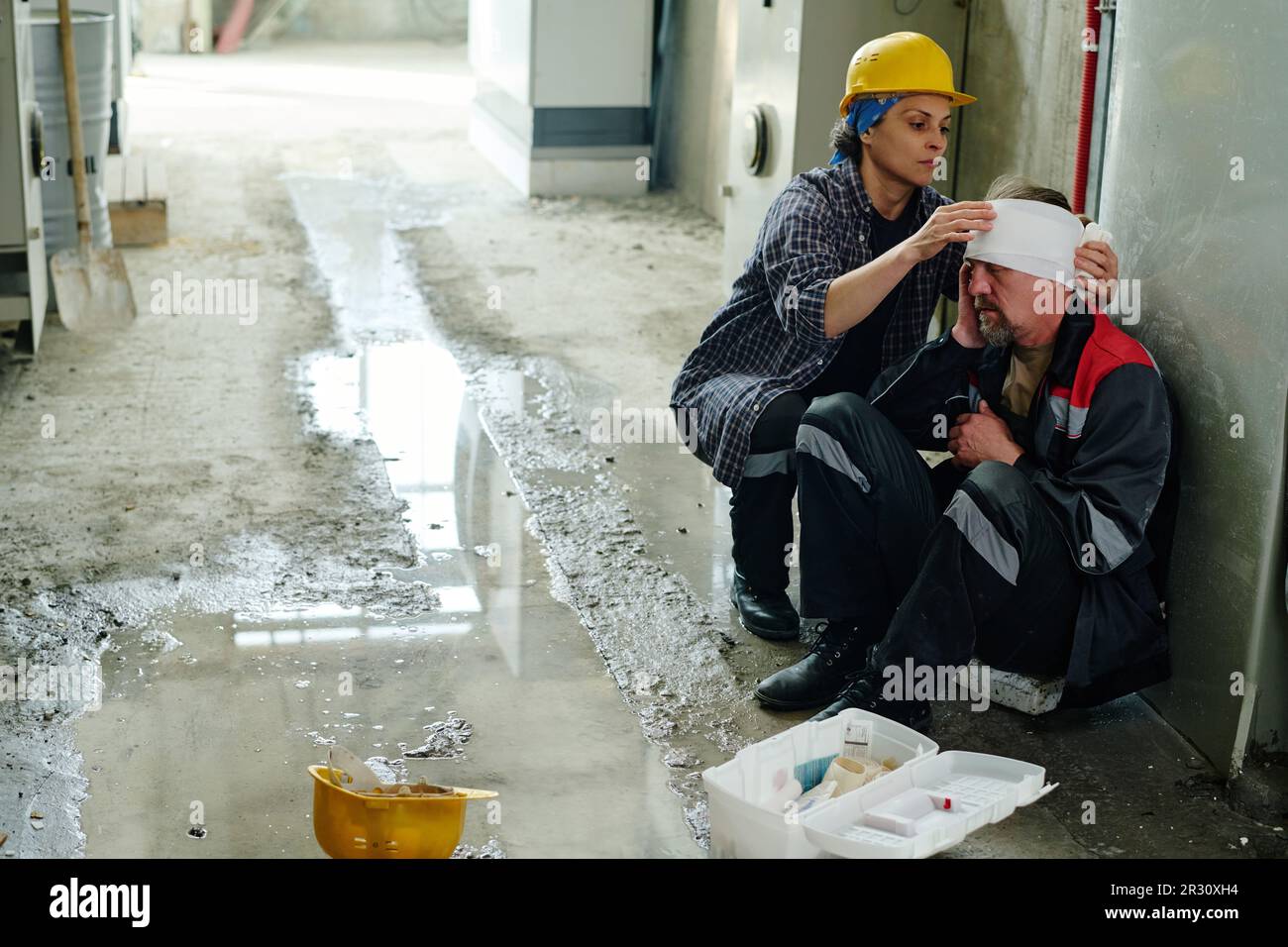 Worker receiving industrial injury in factory and colleague wrapping ...